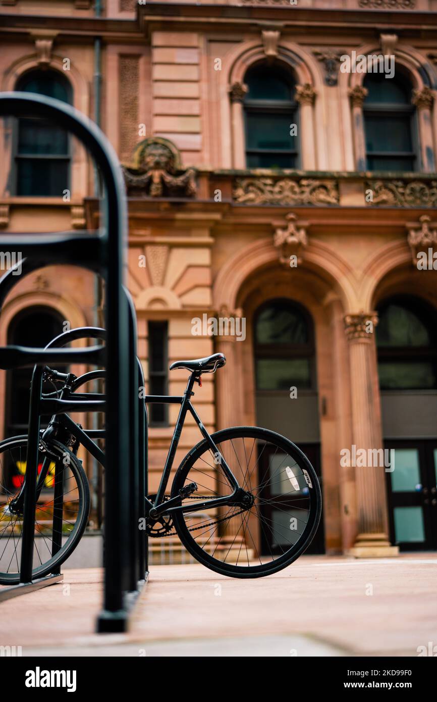 A vertical shot of a black sleek bike parked beside a luxurious ...