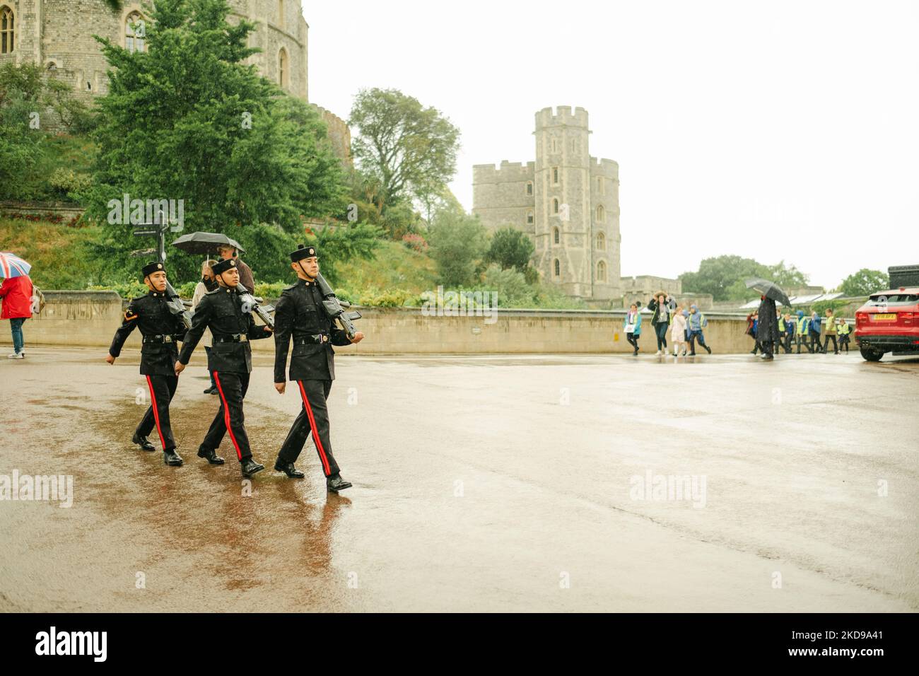 The soldiers in classic red coats march along The Mall in London ...