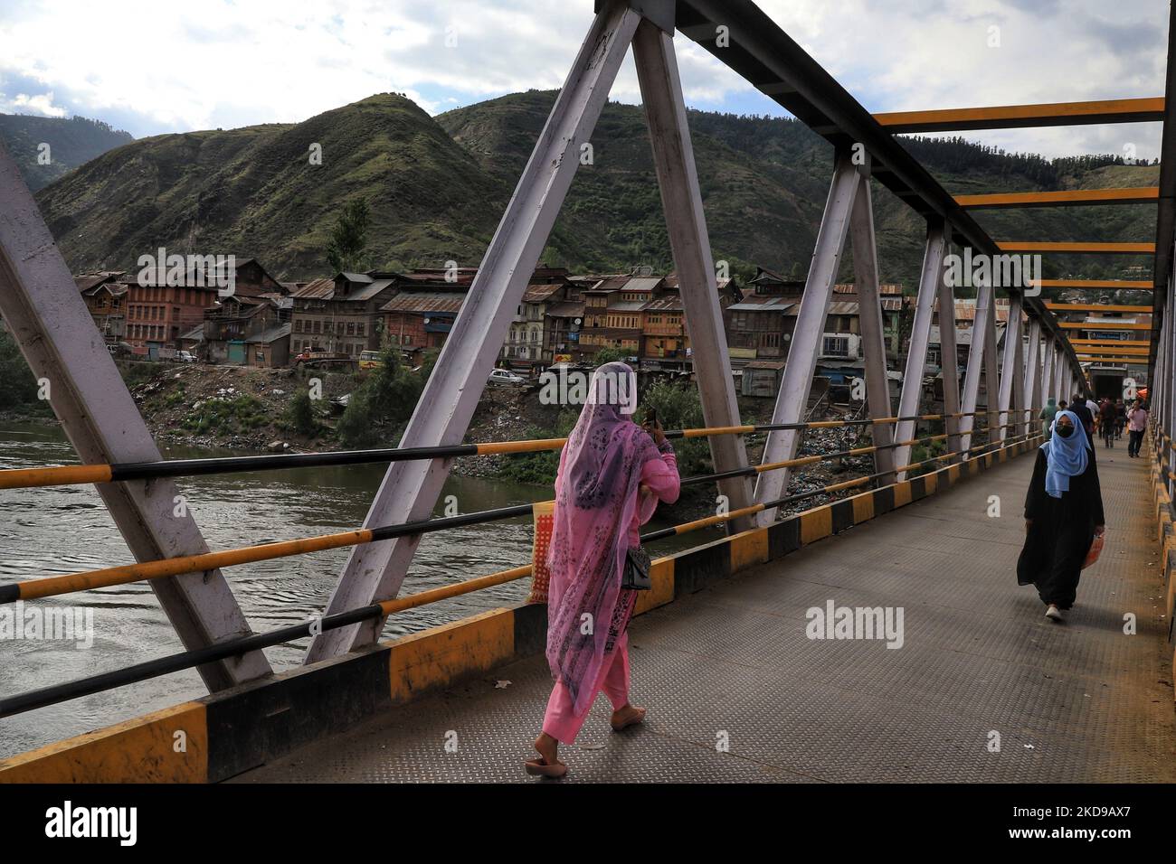 People walk over a bridge as residential houses are seen in Baramulla ...