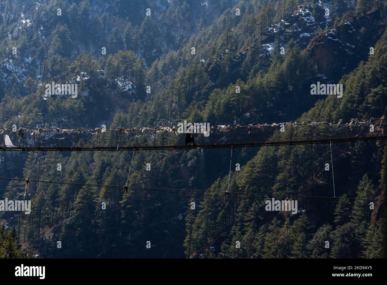 A person crossing a suspension bridge over the Dudh Kosi River, Mount ...