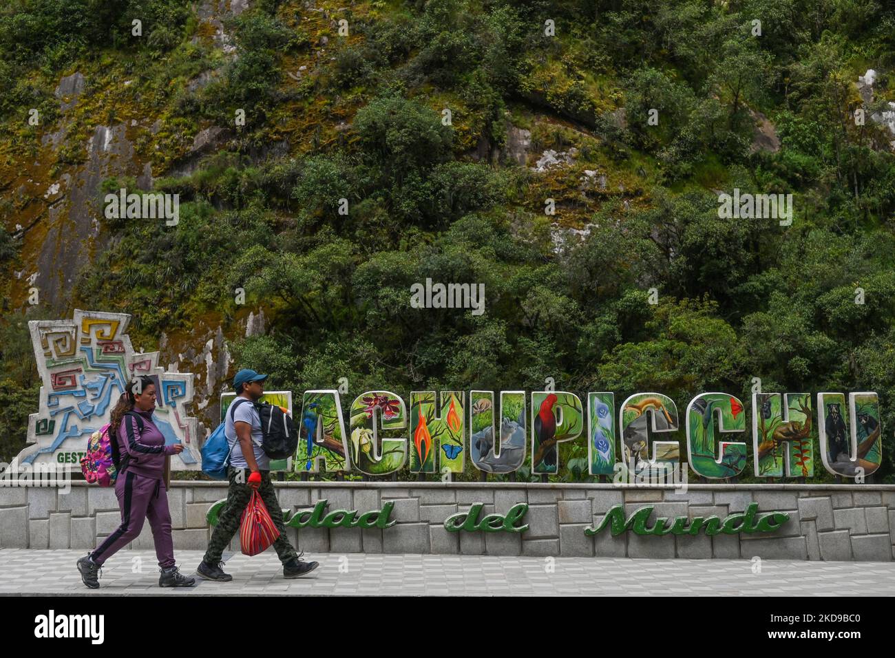 Tourists walk past by letters with the name of Machupichu Peublo in ...