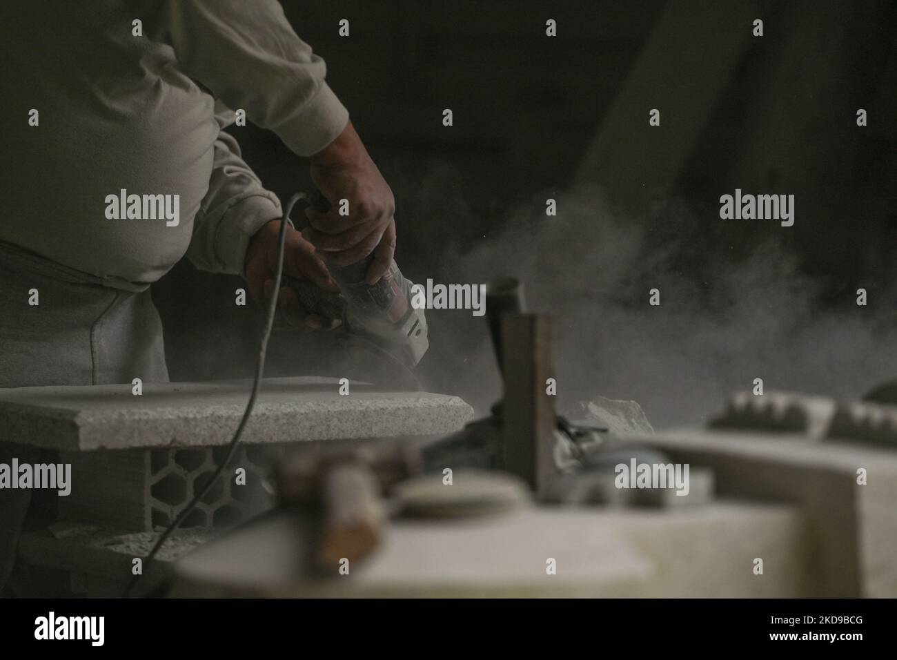 A man cuts and shapes stone products in his workshop in Aguas Calientes ...