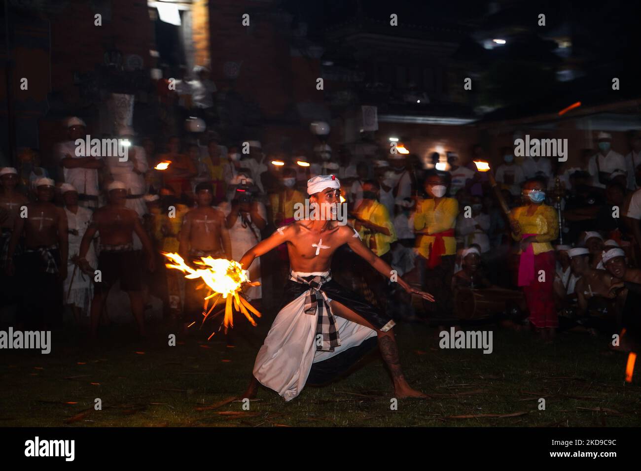 Balinese man hold burnt coconut dried leaves, dances during the fire ...