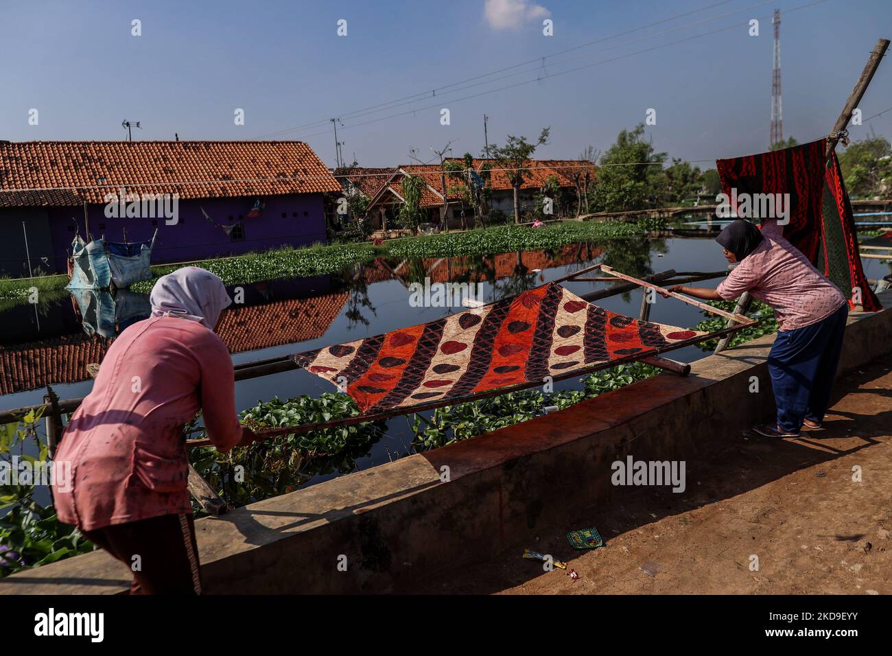Workers dry batik after dyeing process as they make traditional ...