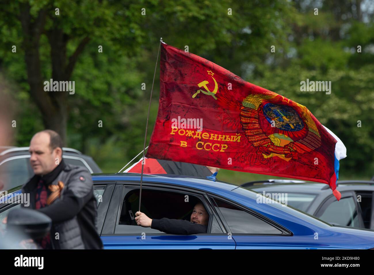 a man holds a communist hammer flag with writing "born in CCCP" drive ...