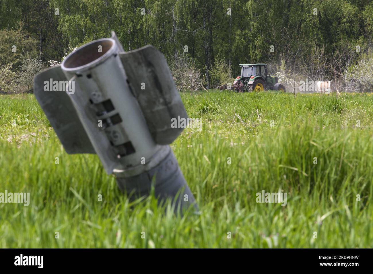 Tractor works on a field close to the detail of a rocket missile on the ...