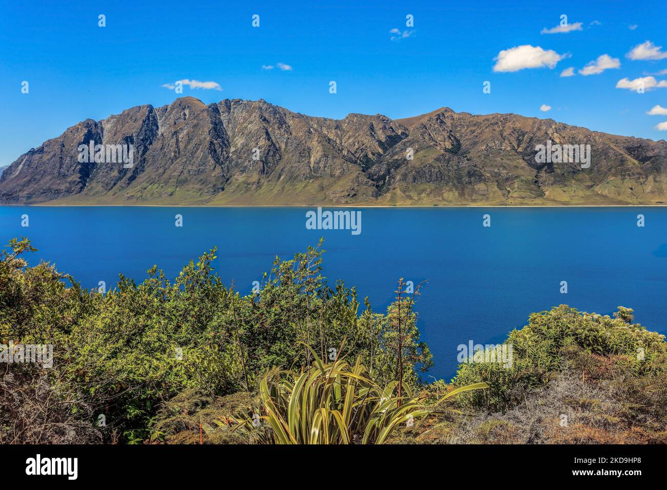 A scenic view of lake Hawea surrounded by mountains and greenery in ...