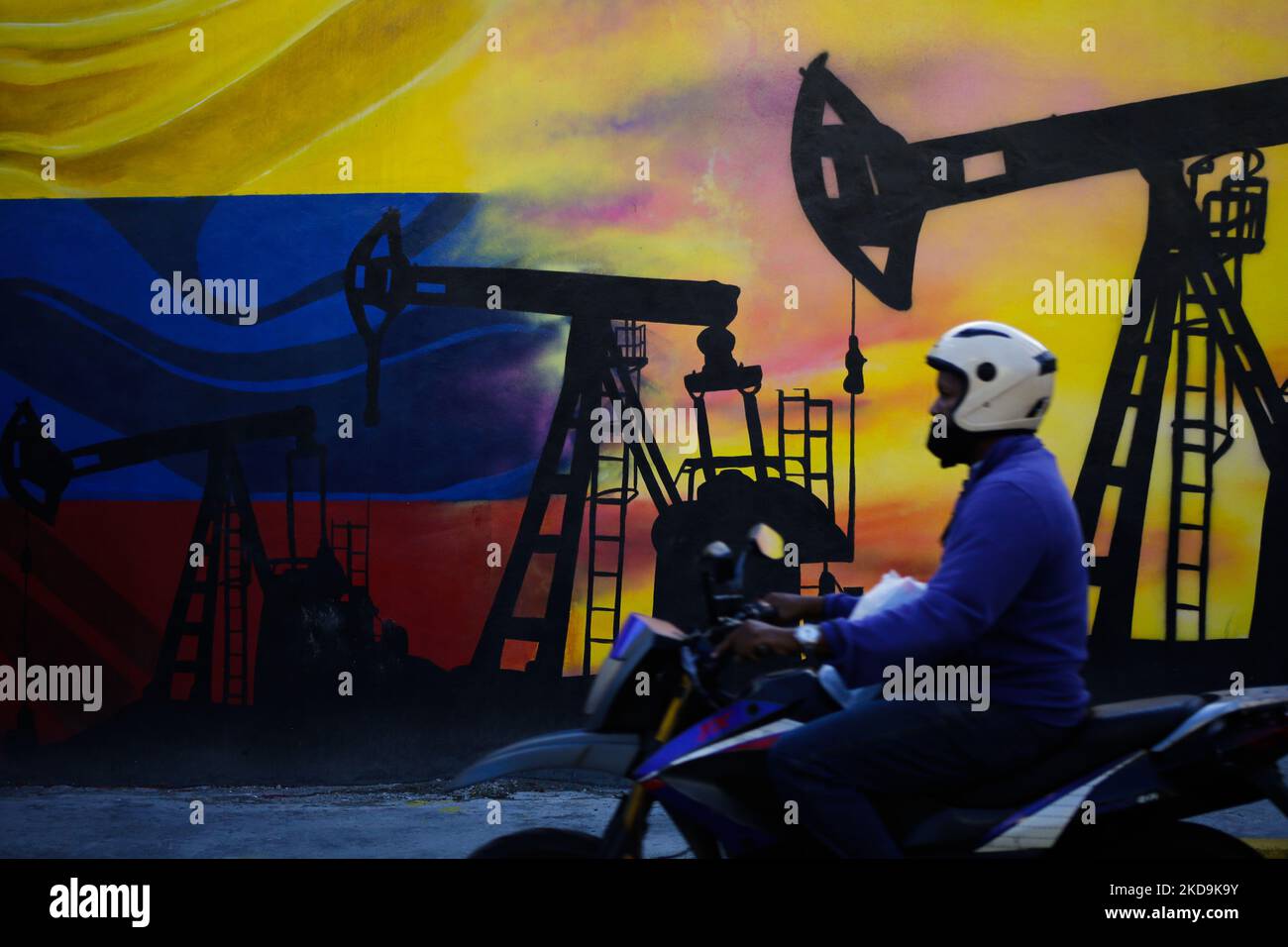 A motorcycle passes in front of an oil-themed mural in Caracas ...