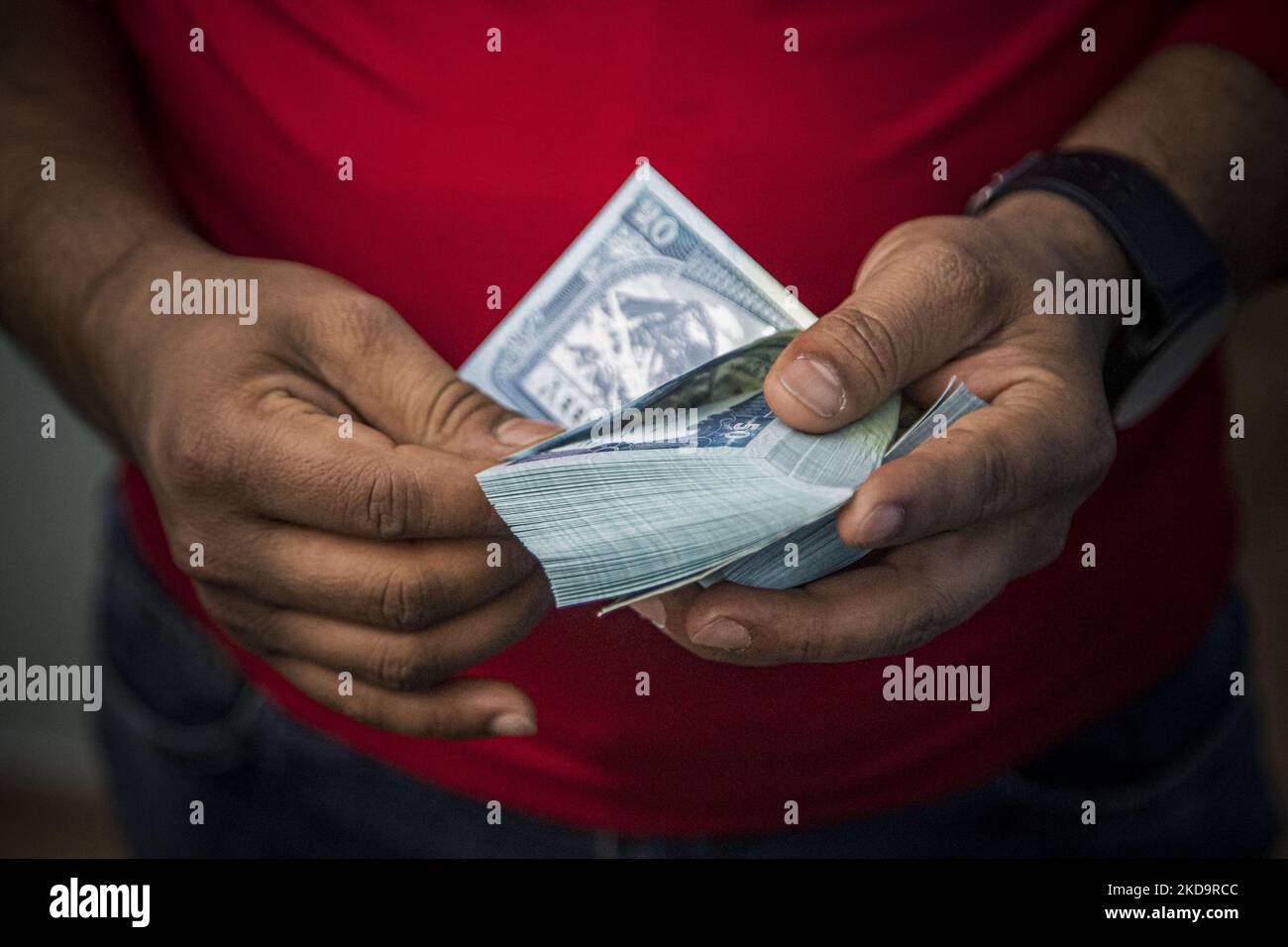 Closeup at a pack of 50 Nepalese Rupees while a man behind the counter ...