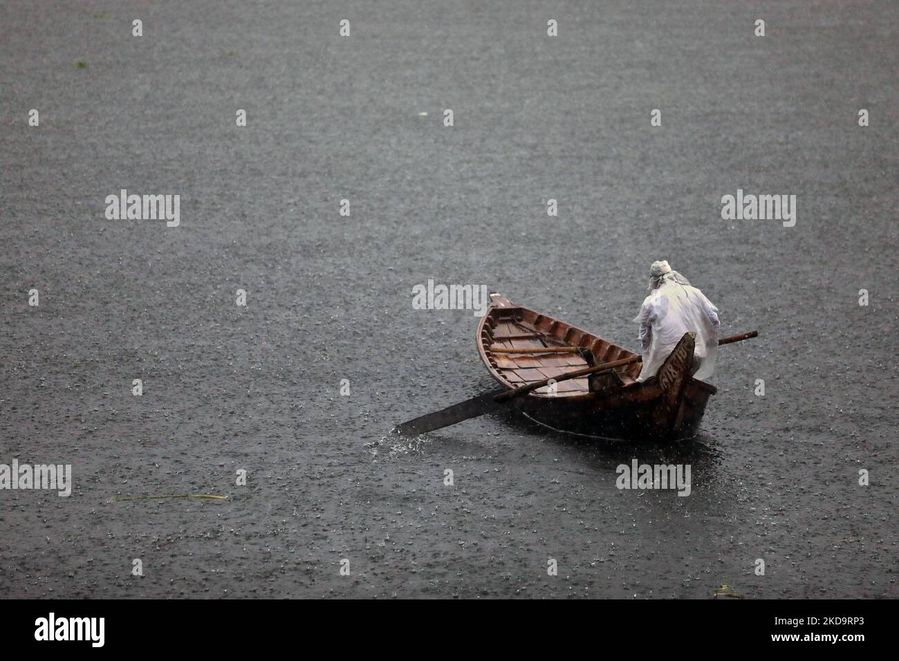 A boatman crosses the river Buriganga by boat during rain in Dhaka ...