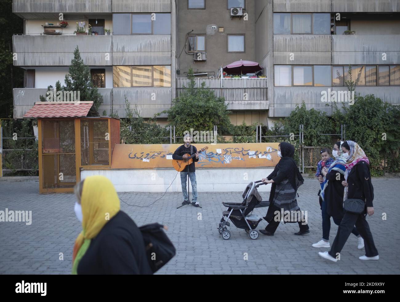 An Iranian street musician plays guitar while standing in front of a ...