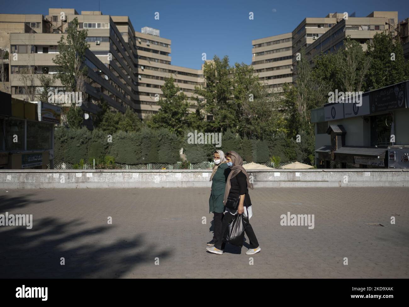 Two Iranian women walk along an area near housing complexes in the ...
