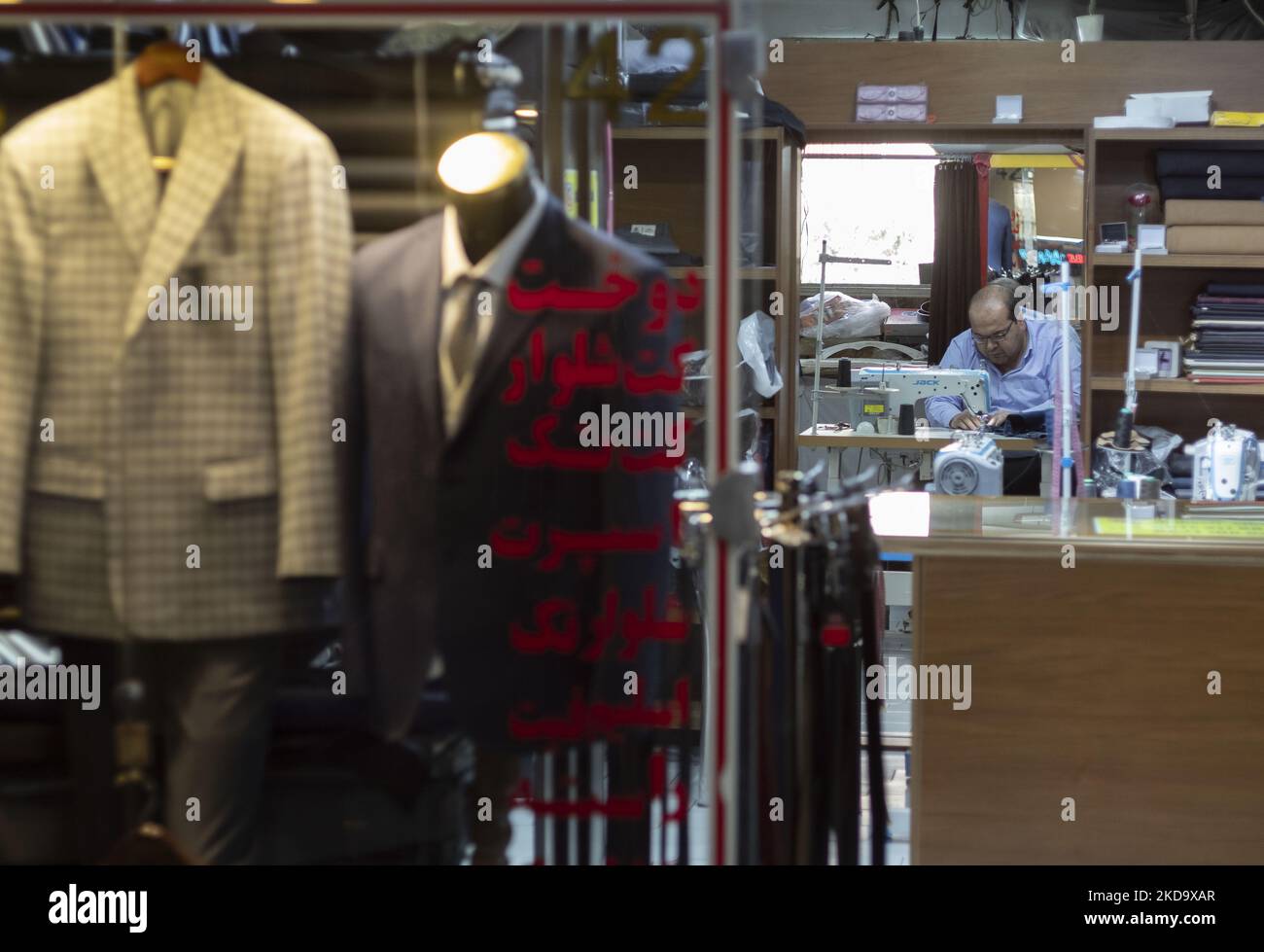 An Iranian tailor works at his small tailoring workshop in a shopping ...