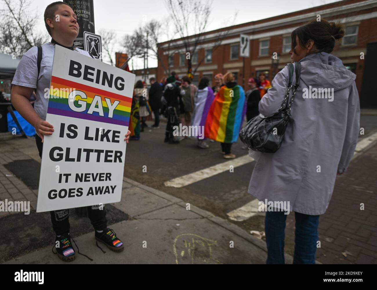 An activist holds a poster with words 'Being Gay Is Like Glitter. It ...
