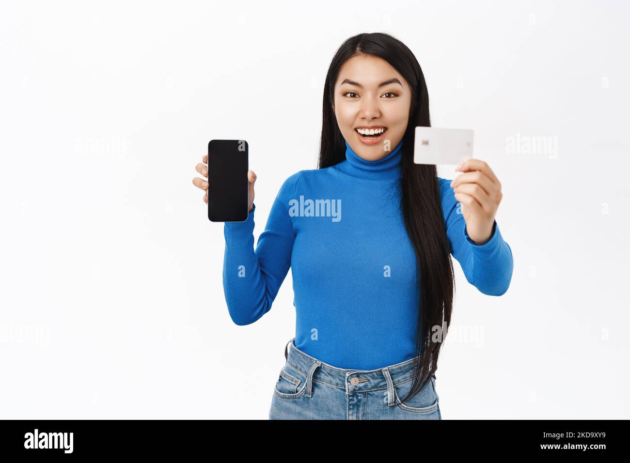 Smiling korean woman shows mobile phone screen and credit card, online ...