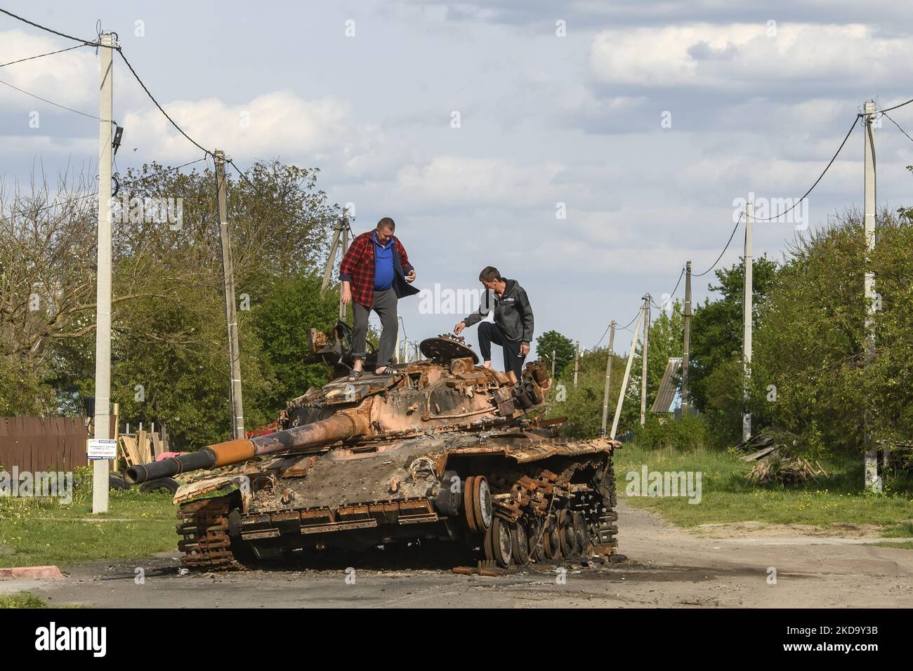 Local men explore burned tank on the street in Zahaltsi village near ...