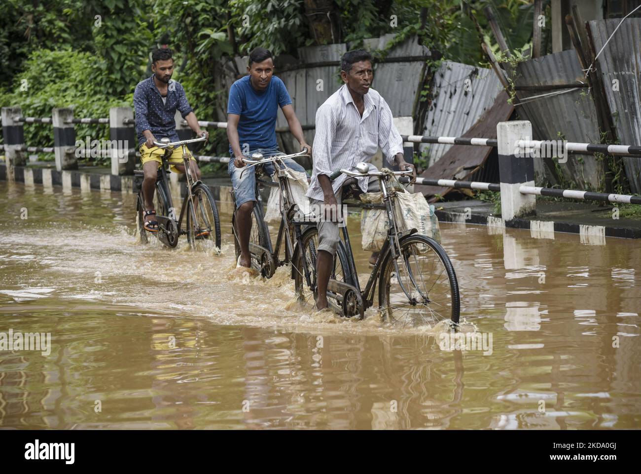 Commuters make their way on a waterlogged street after a heavy rainfall ...
