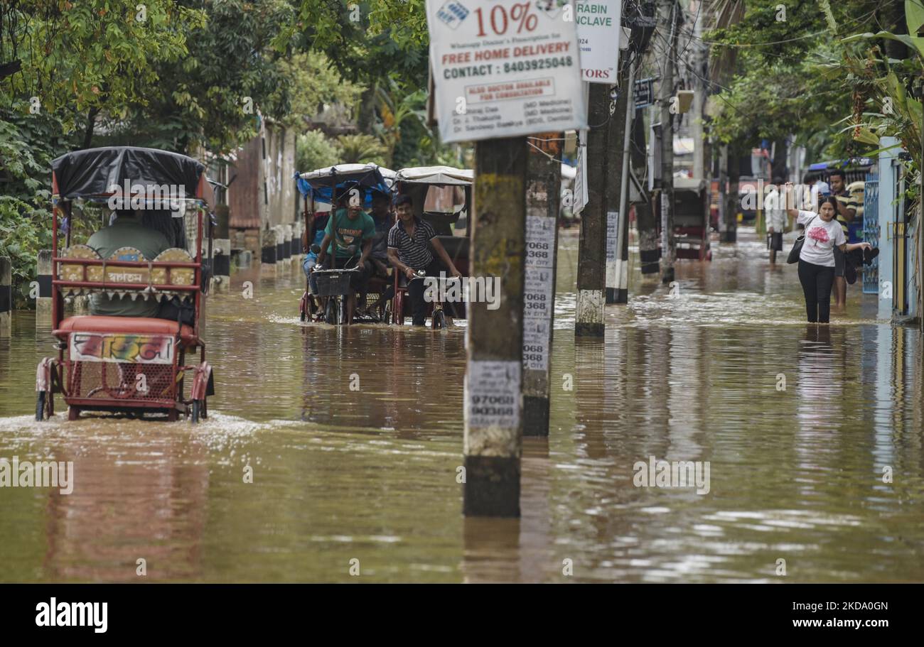Commuters make their way on a waterlogged street after a heavy rainfall ...