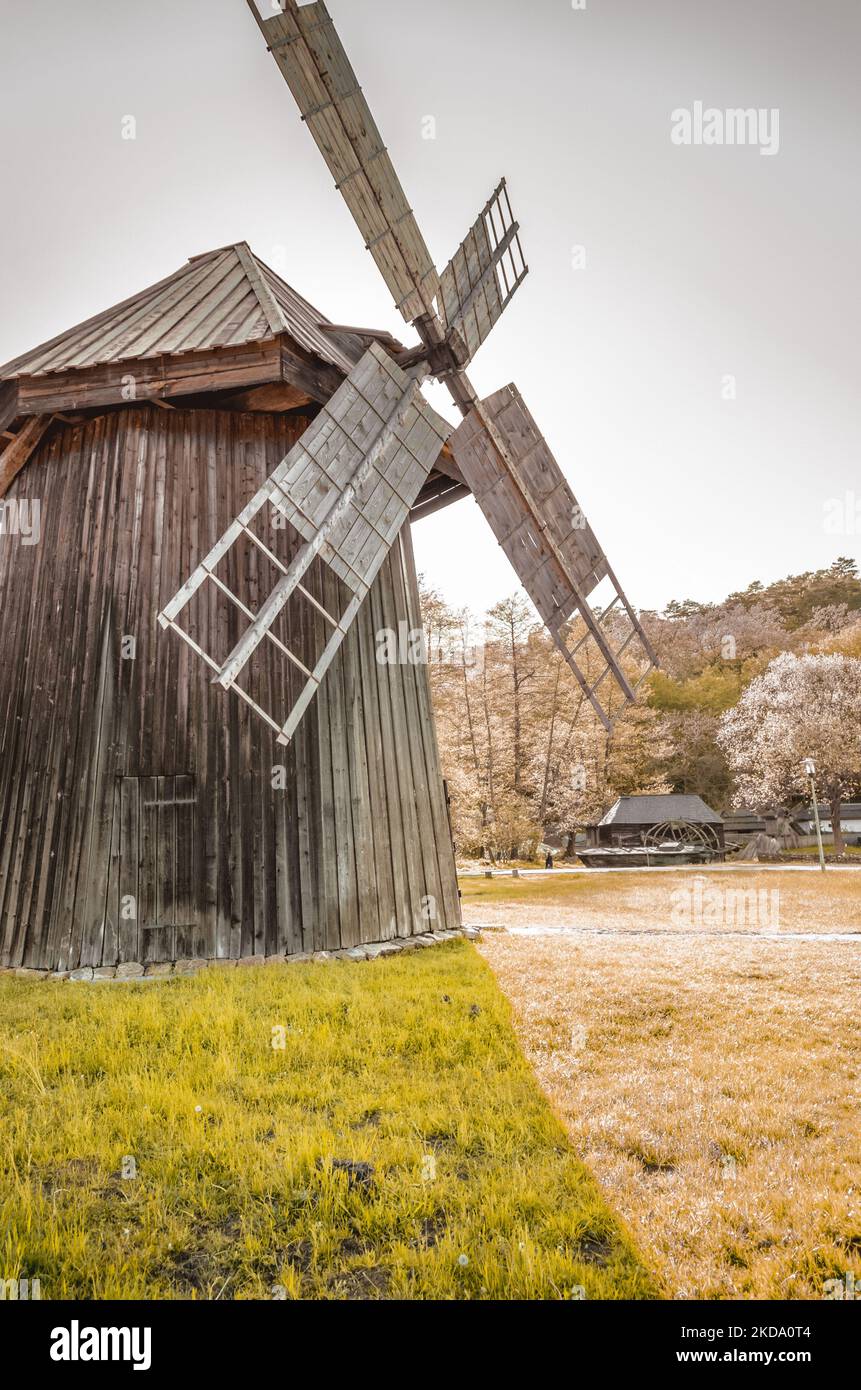 A vertical shot of a wooden windmill on a field in a rural area in ...