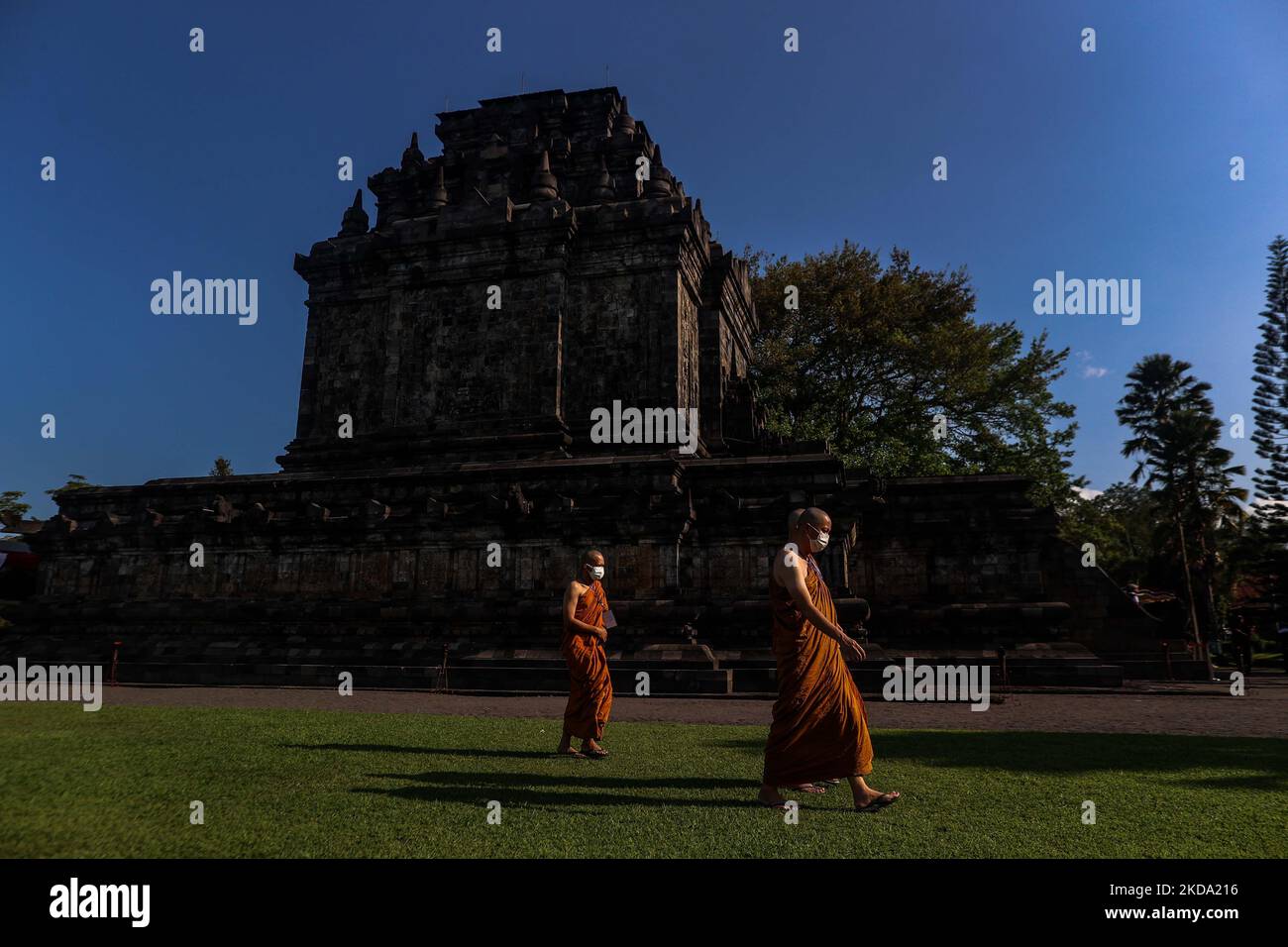 Buddhist monks walk around Mendut temple during the holy water ceremony ...