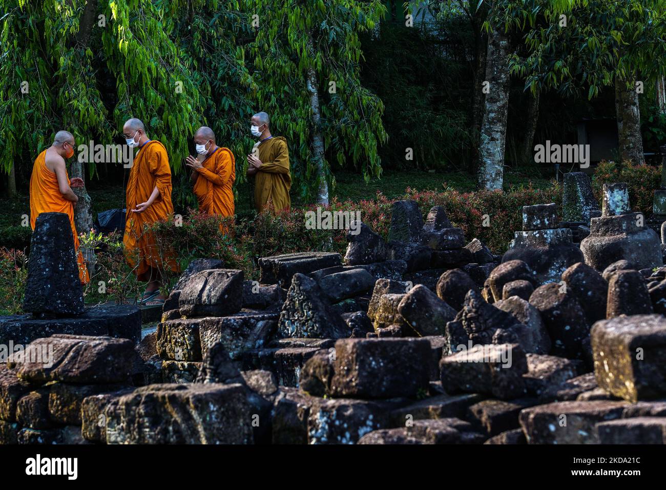 Buddhist monks walk around Mendut temple during the holy water ceremony ...