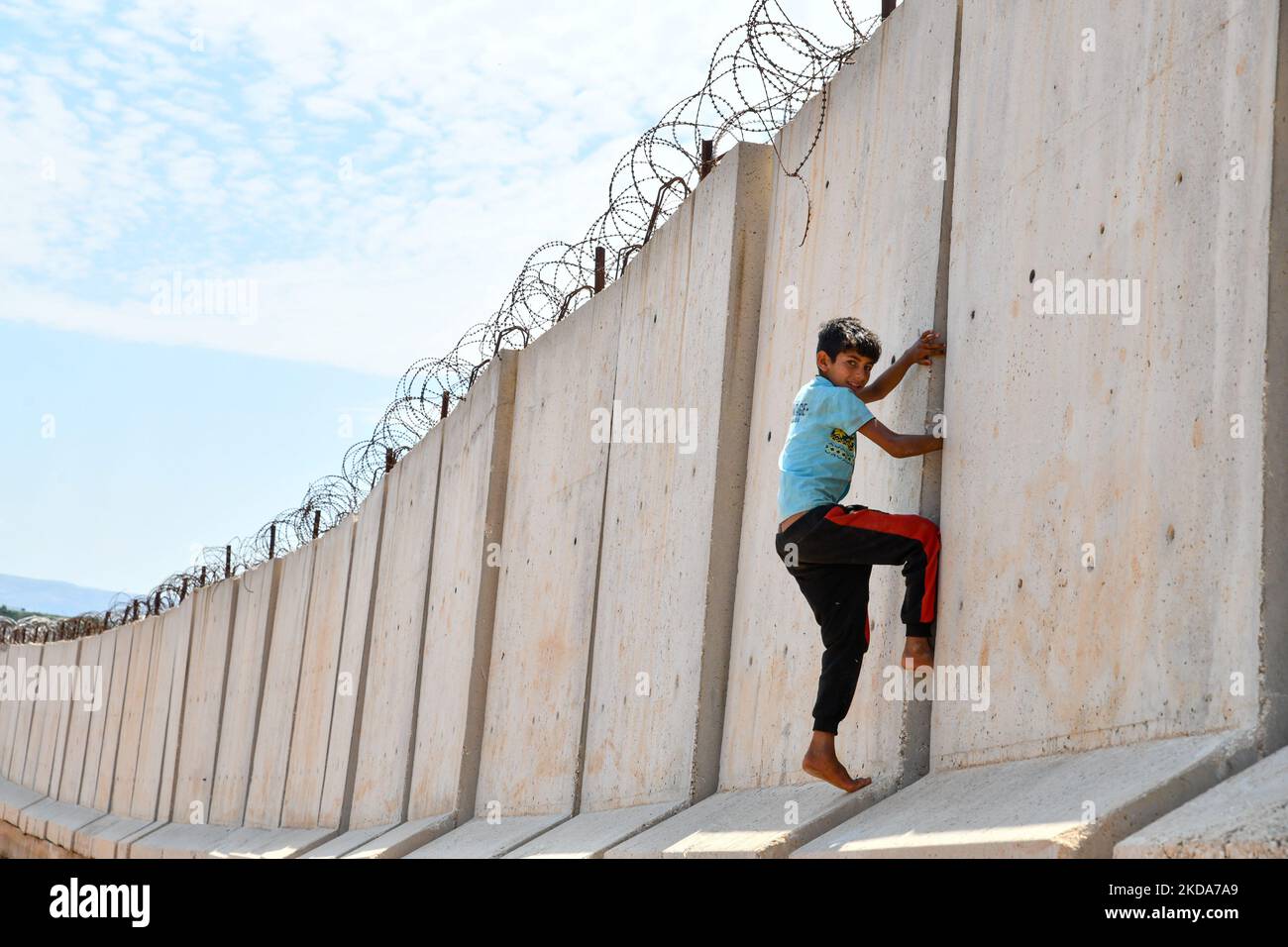 Camp children play on the wall separating Syria and Turkey near the ...