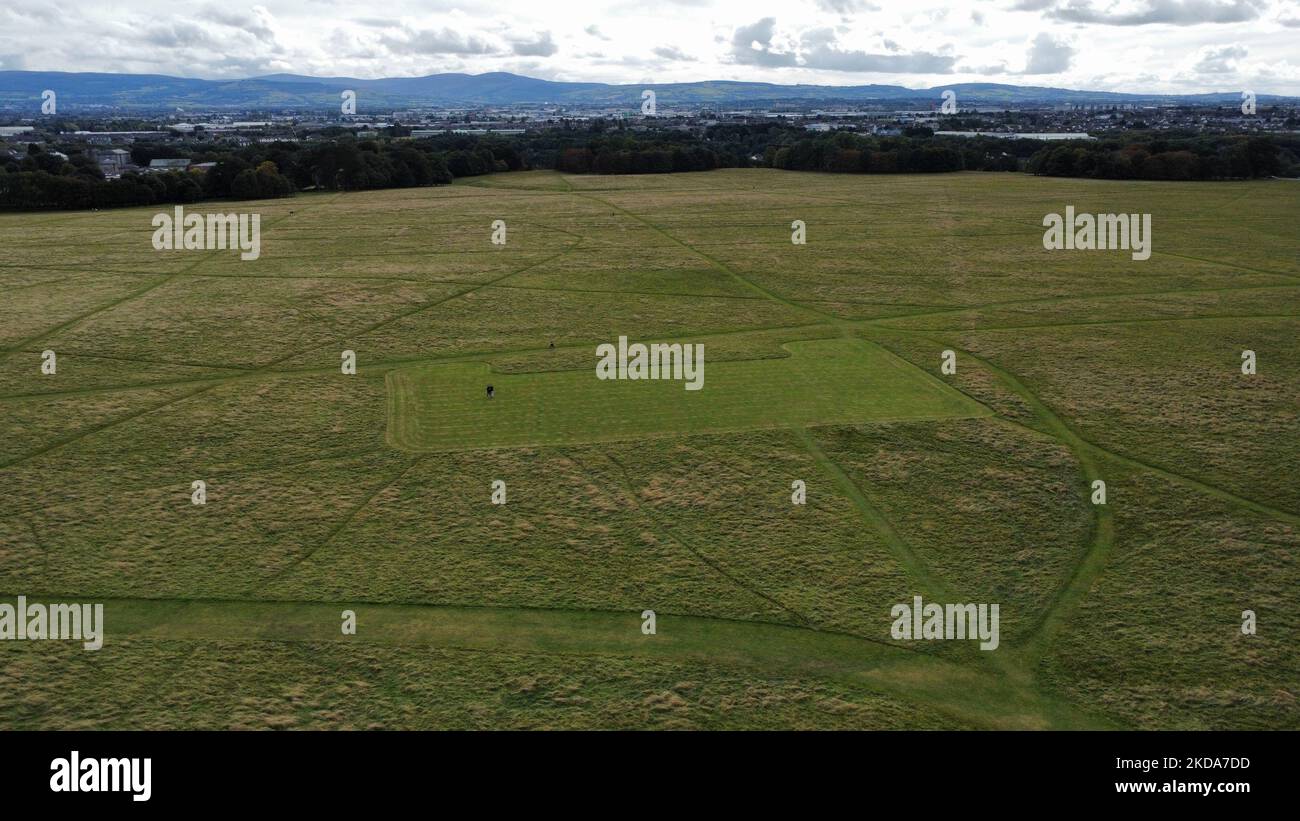An aerial view of vast open green field with buildings at a distance ...