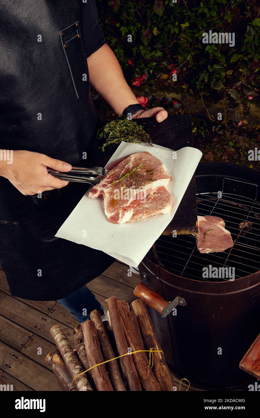 male chef placing the meat on the spit ready to prepare lunch or dinner ...