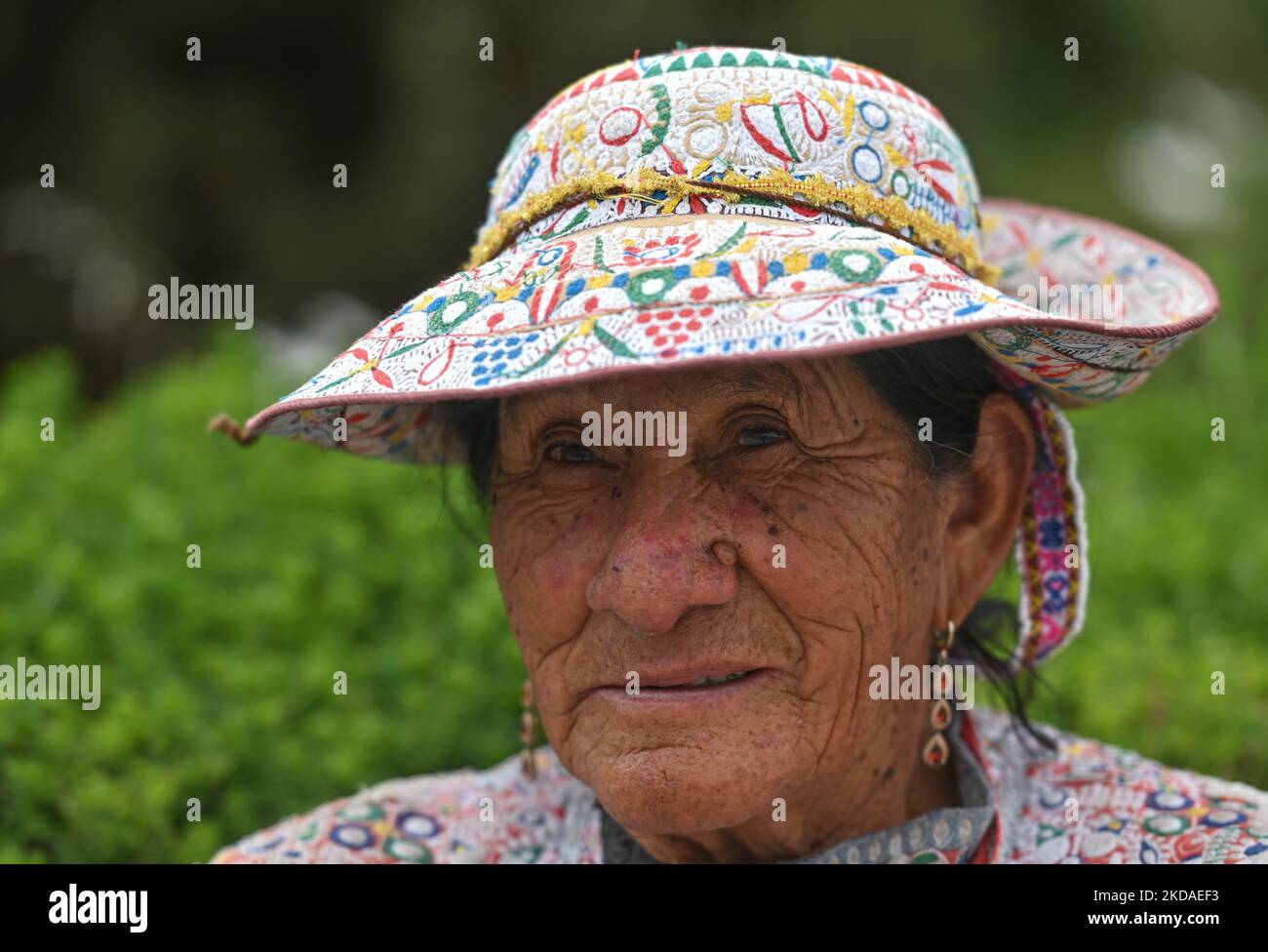A local woman in a traditional dress sitting on a public bench in a ...