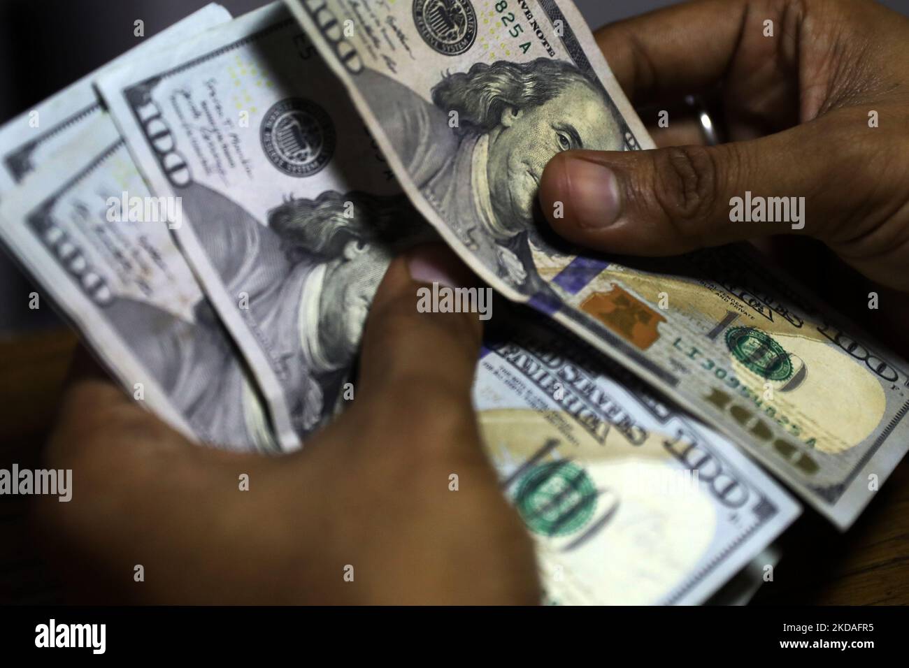A customer counts US Dollars at a money exchange booth in Dhaka ...