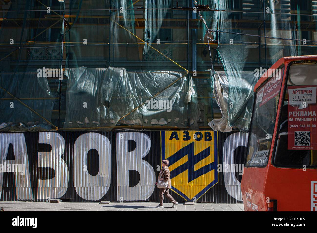 A woman walks by street art depicting the Azov Battalion symbol in Lviv ...