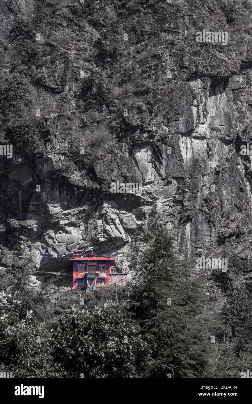 A vertical shot of the red cottage against the background of a cliff ...