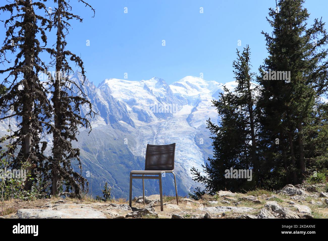 A beautiful shot of a chair on a stone mountain with the Mont Blanc ...