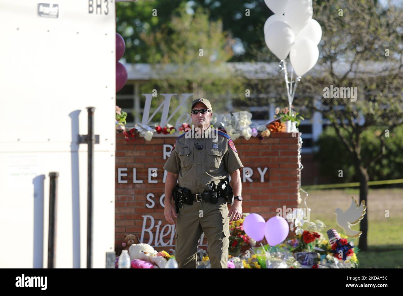 An officer is seen in front of the Robb Elementary School sign in ...
