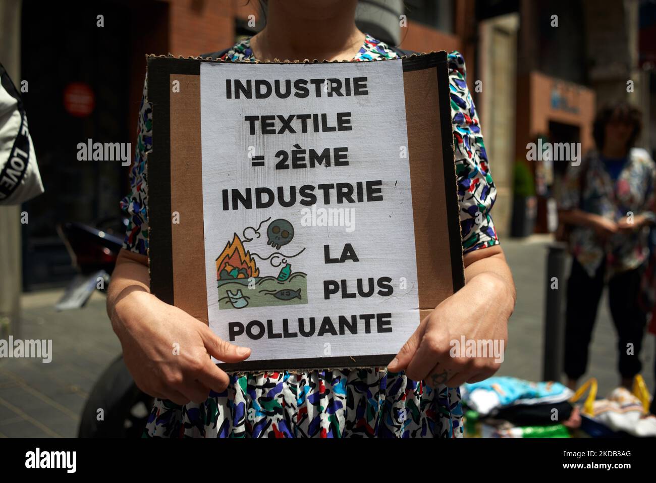 A woman holds a cardboard reading 'Textile industry = 2nd most ...