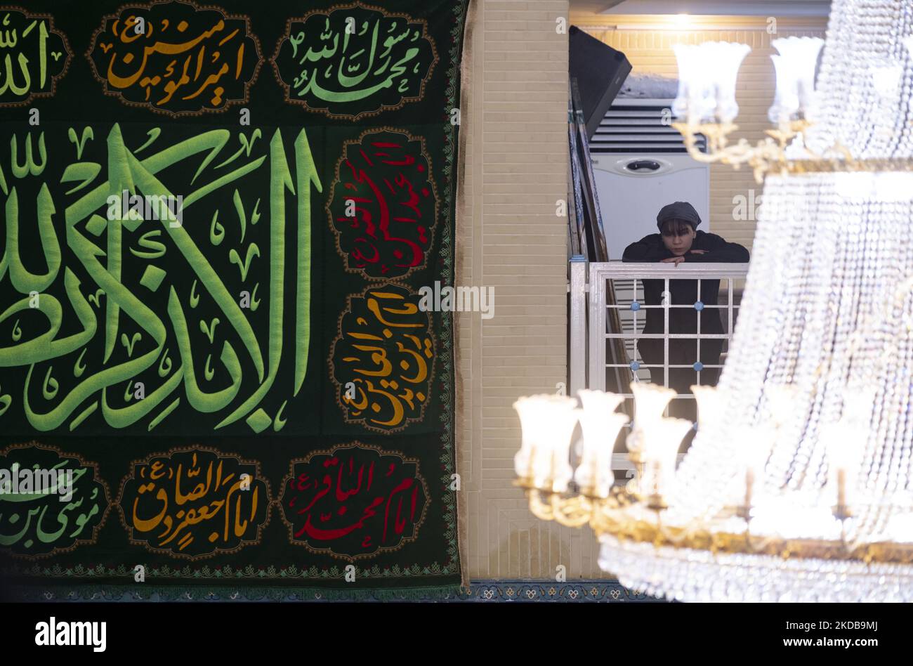 An Iranian young woman stands next to a religious flag in a mosque in ...