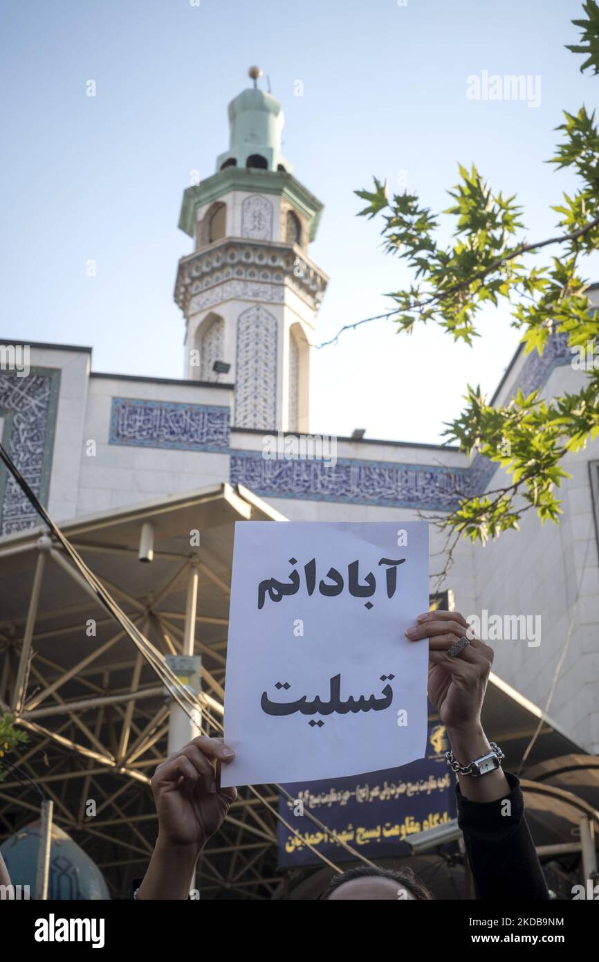 An Iranian woman holds-up a placard with a Persian script reads ...
