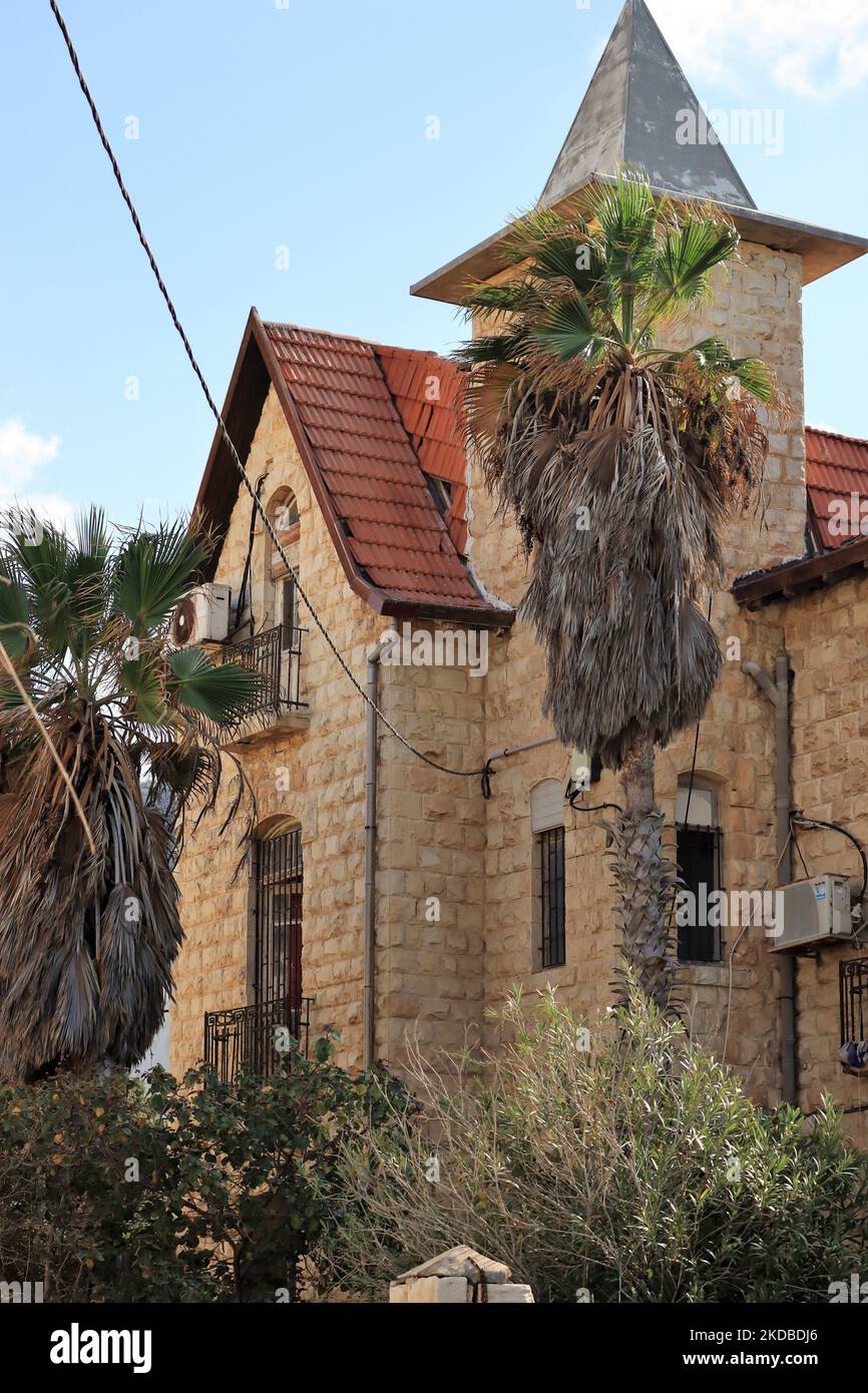 A vertical shot of a building with tile roof and a tower with palm ...