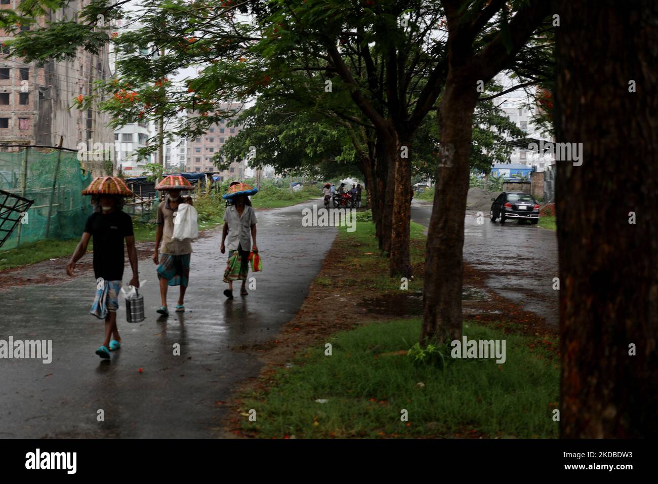 Day laborers walk through a lite rain to their workplace in Aftabnagar ...