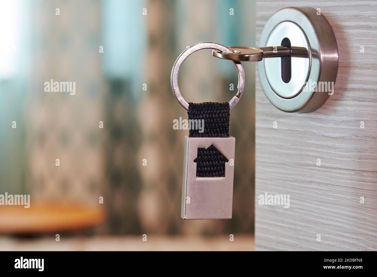 Key with a house keyring in the door keyhole. Opened door to the room ...
