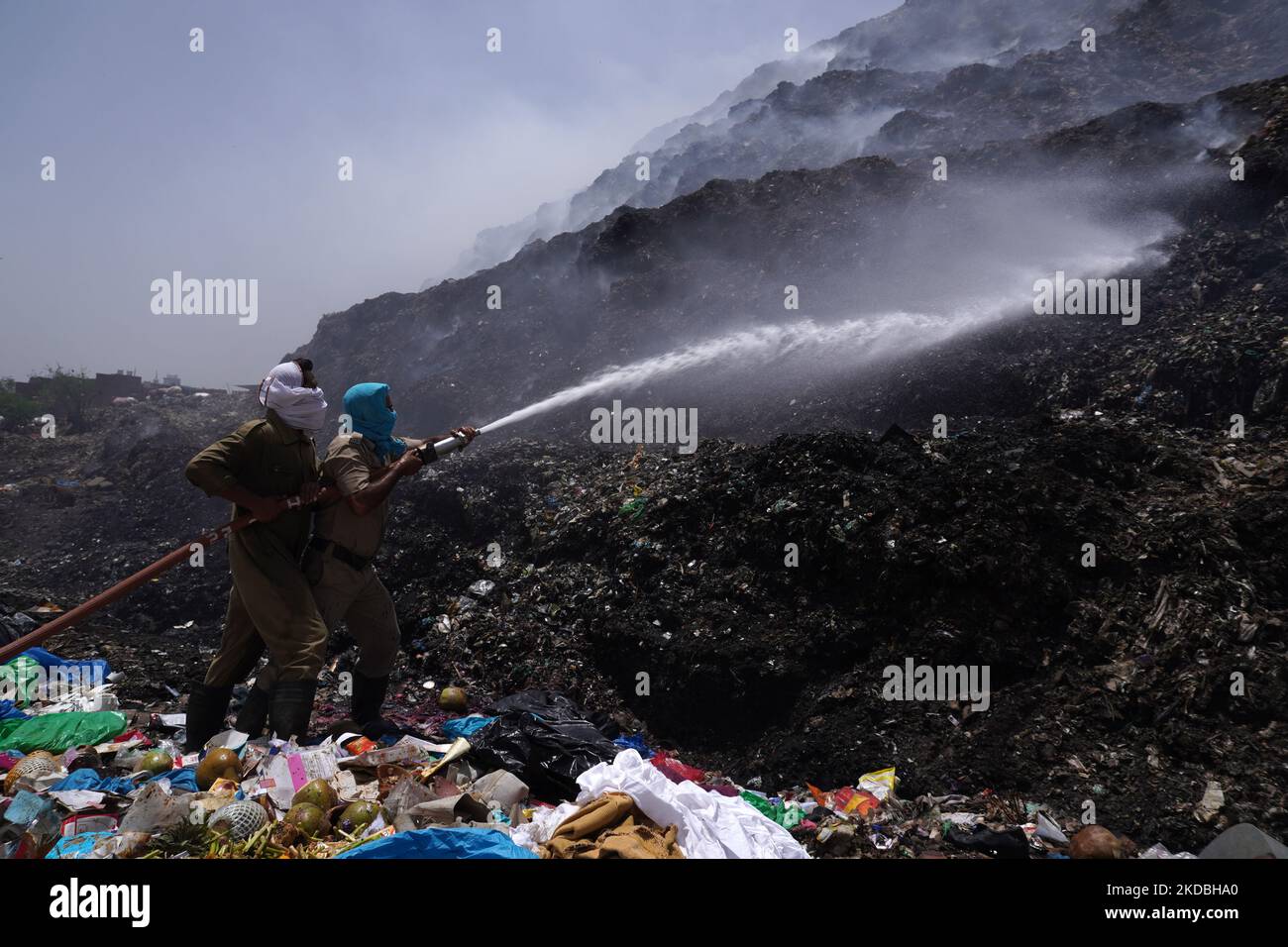 Firefighters try to douse fire as smoke billows from a burning garbage ...