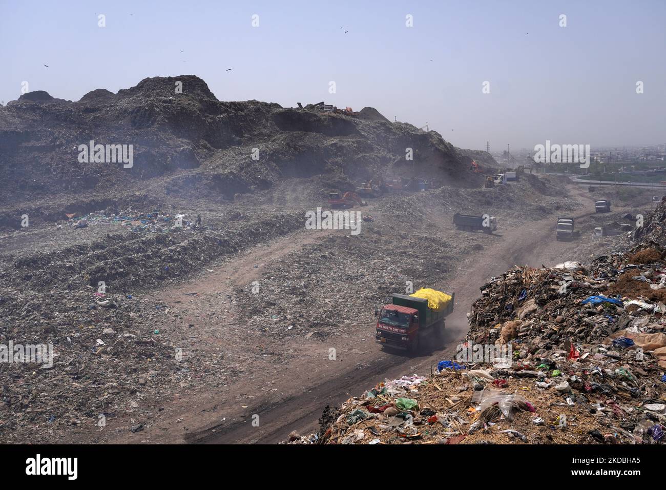 A truck transports garbage to dump as smoke billows from a burning ...