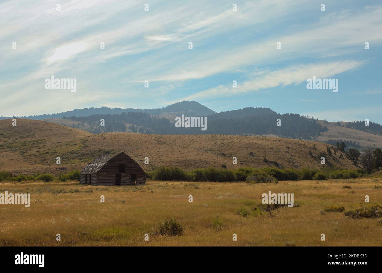 A small abandoned wooden house in the field surrounded by mountains ...
