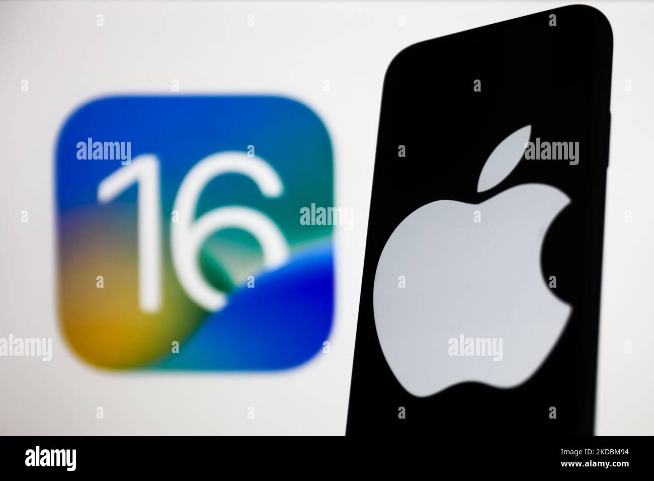 Apple logo displayed on a phone screen and iOS 16 logo displayed on a ...