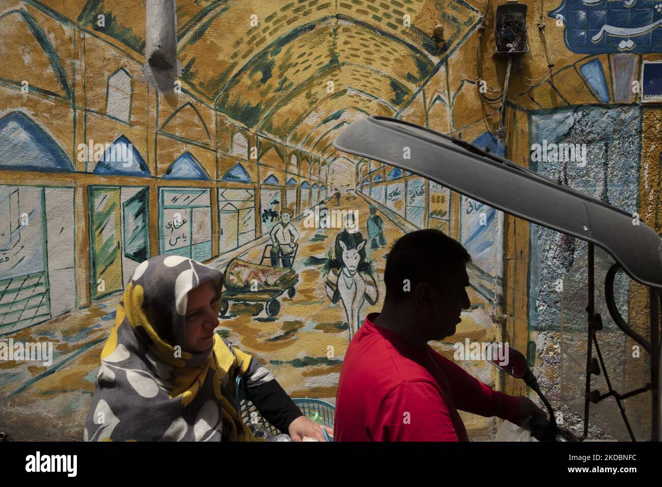 An Iranian couple ride motorcycle past a mural near the Shapour Bazaar ...