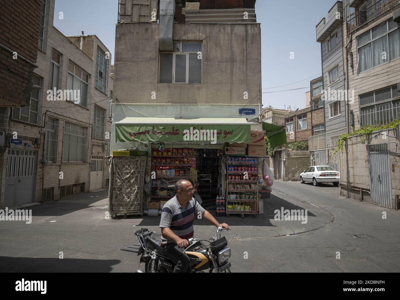 An Iranian man rides motorcycle past a small local supermarket near the ...