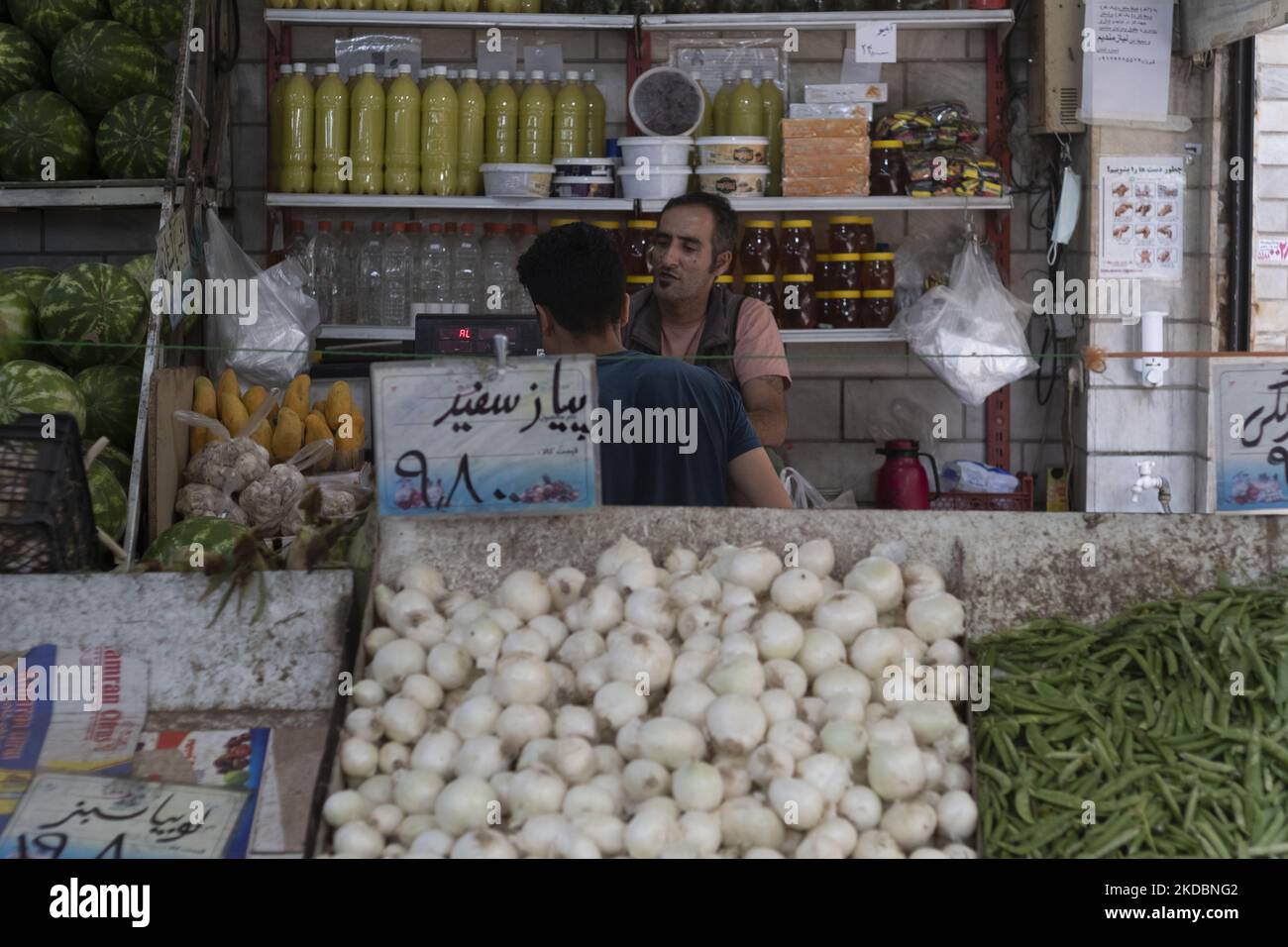 An Iranian greengrocer talks to a client at his fruit and vegetable ...