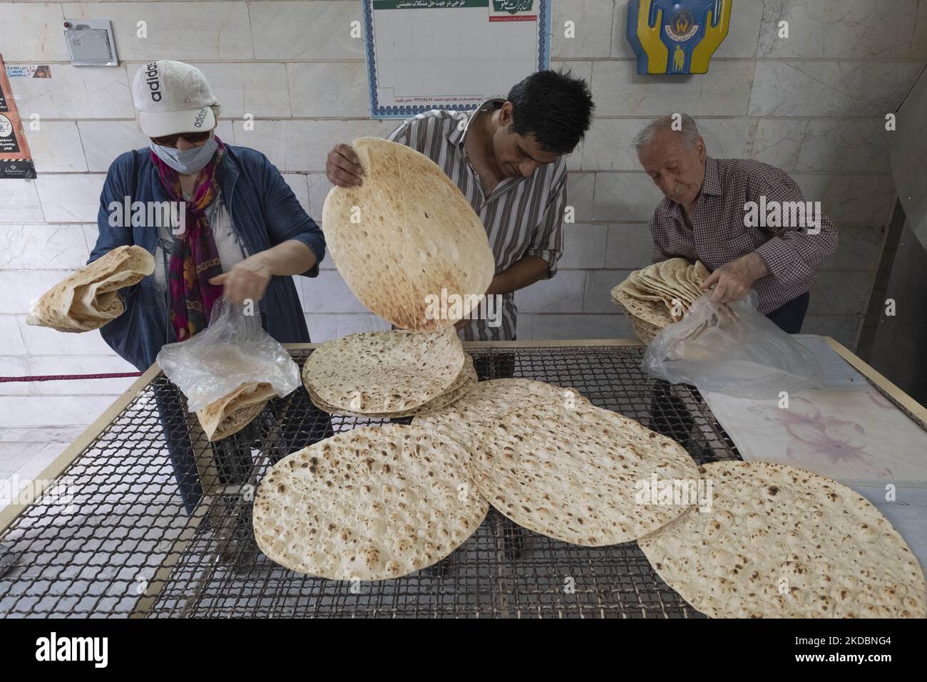 Iranian people collect bread while shopping at a bakery near the ...