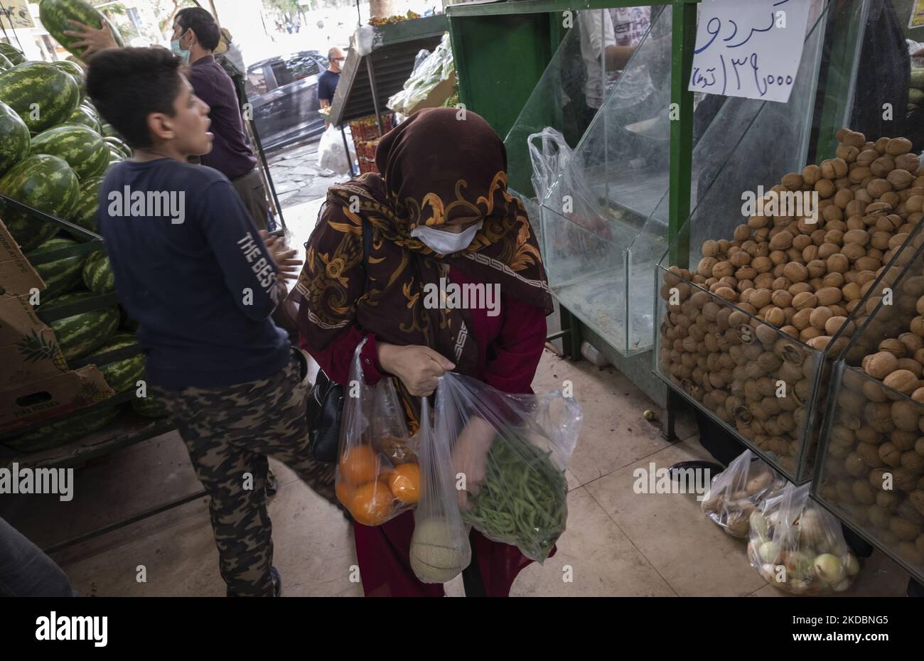 An Iranian woman checks purchases while shopping at a fruit and ...