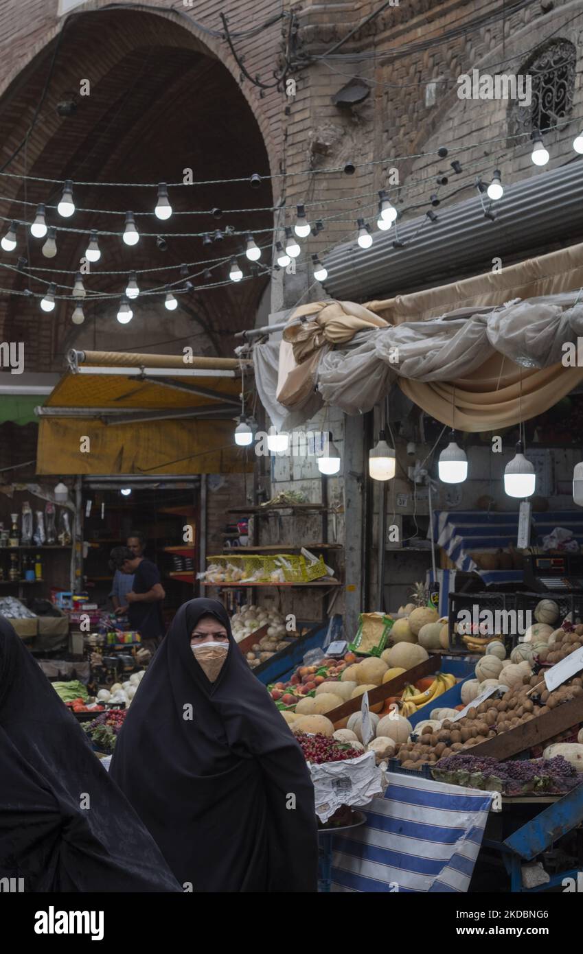 A veiled Iranian woman walks past a fruit shop while shopping at the ...